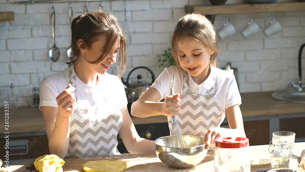 Two sisters cooking together. Elder sister showing younger how to mix ...