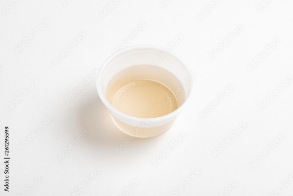 A fresh urine sample in a small round plastic cup container set on a ...