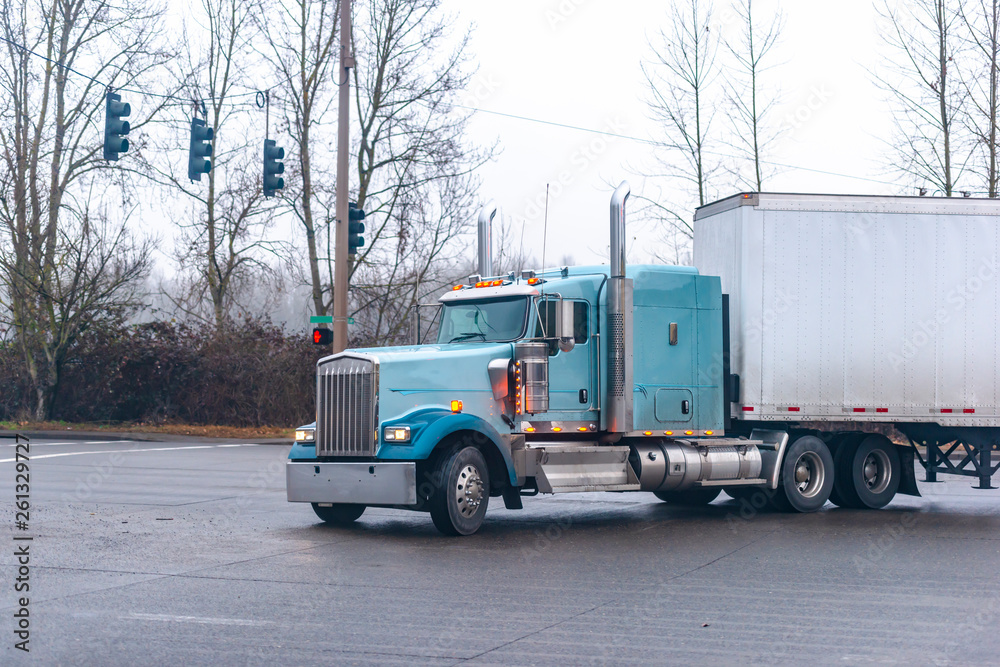 Blue big rig classic American semi truck with turned on headlights ...