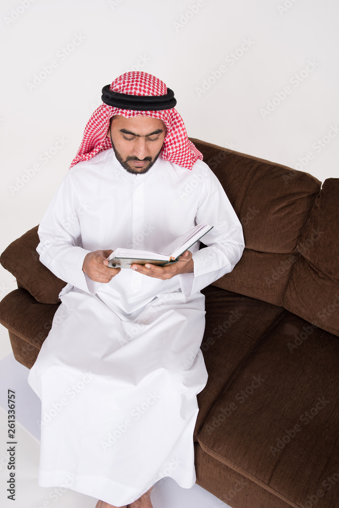 Arab Muslim man sitting on sofa chair and reading the holy Quran Stock ...