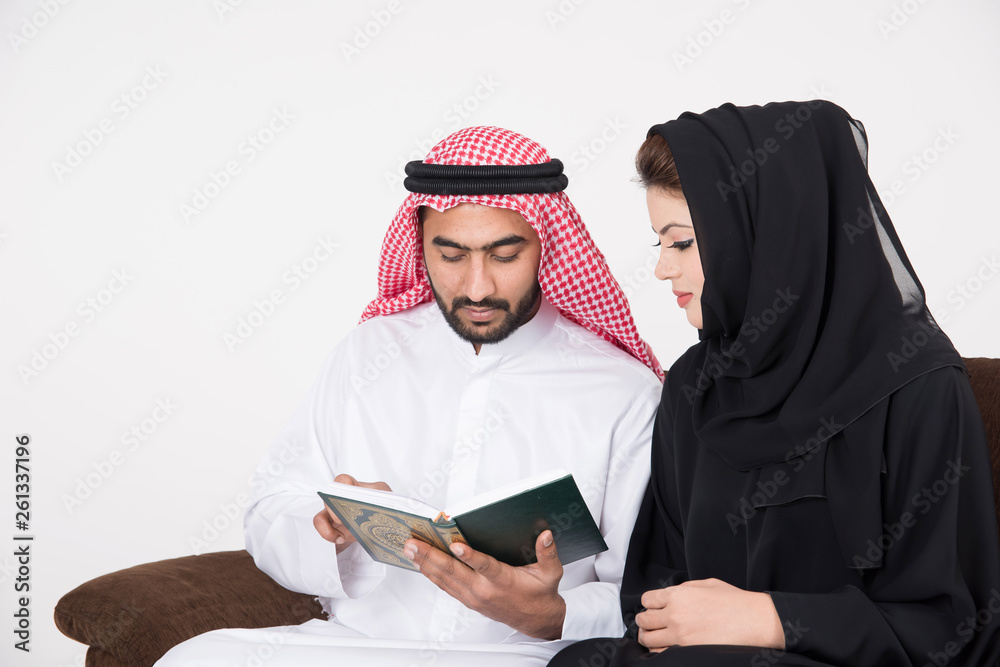 Foto de Arab man reading from the Holy Quran for his wife while sitting ...