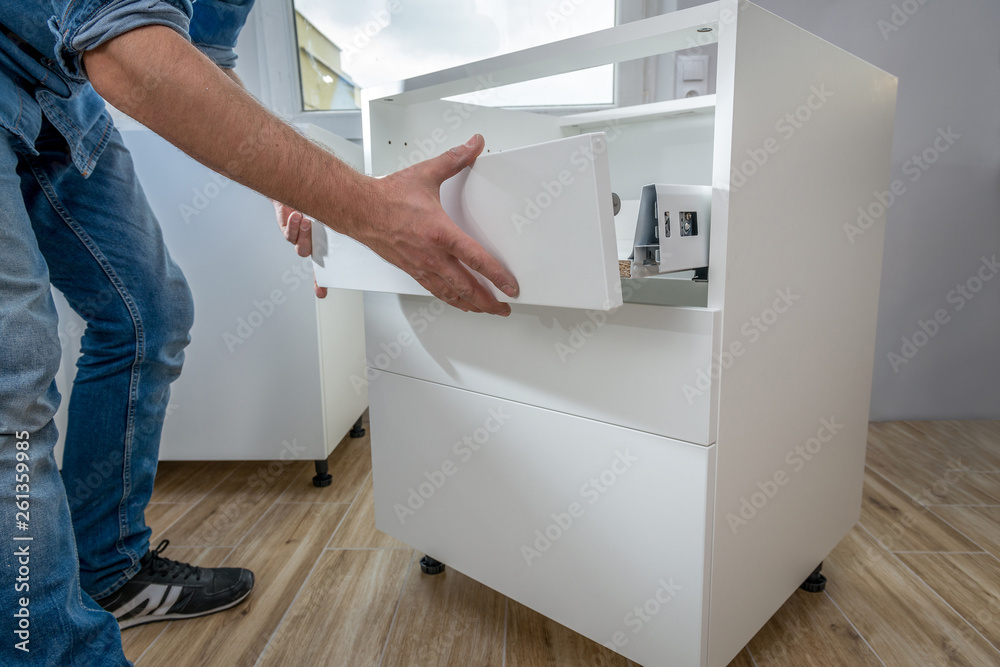 Installation of modern kitchen furniture. A young worker installs a ...