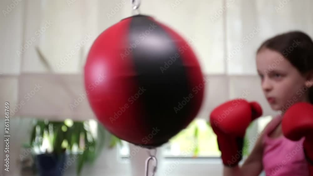 Little girl in red boxing gloves punching double end striking bag ...