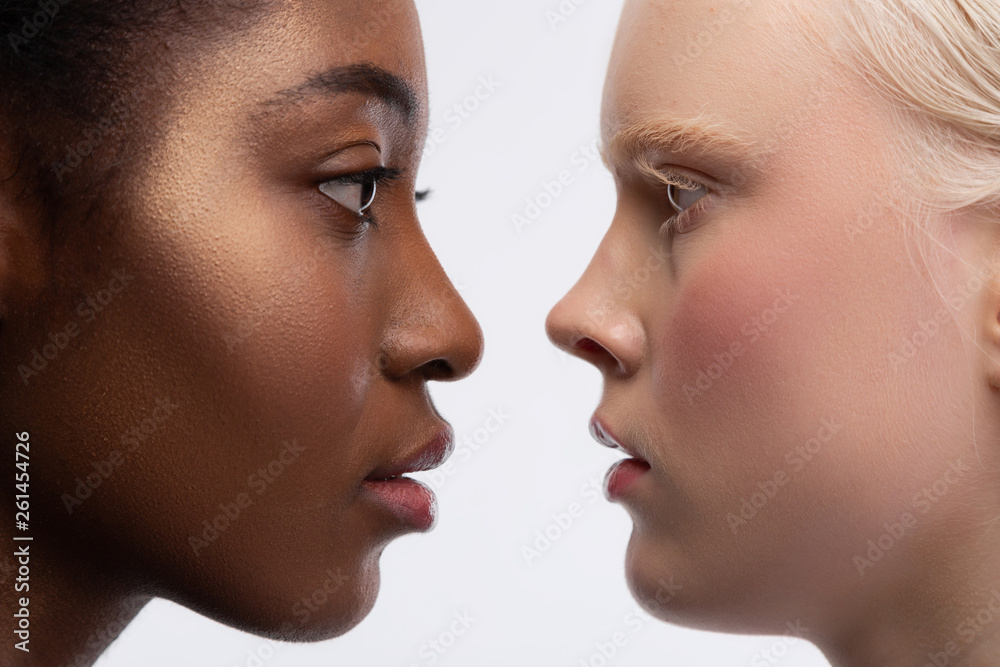 Two young women with different skin color looking into eyes Stock Photo ...