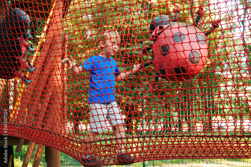Happy boy overcomes obstacles in rope adventure park. Summer holidays ...