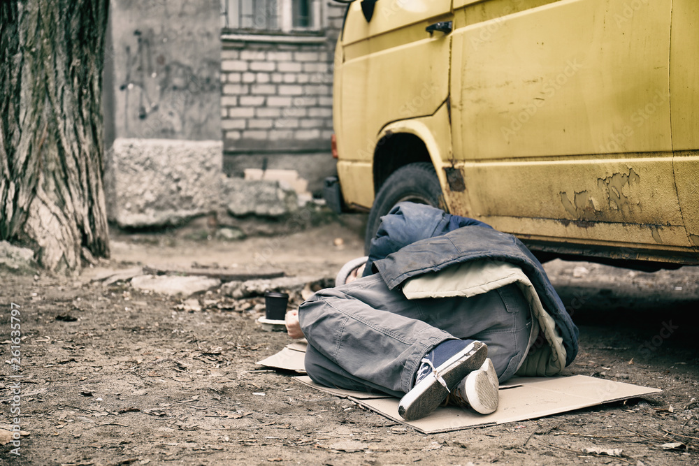 Poor homeless man lying near van outdoors Stock Photo | Adobe Stock