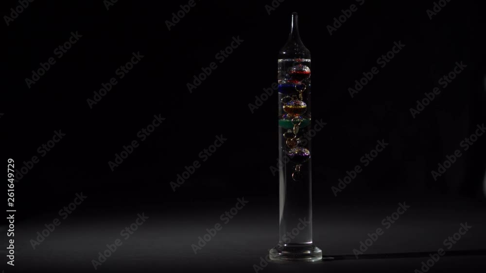 Galileo thermometer shows temperature change moving in real time, glass ...