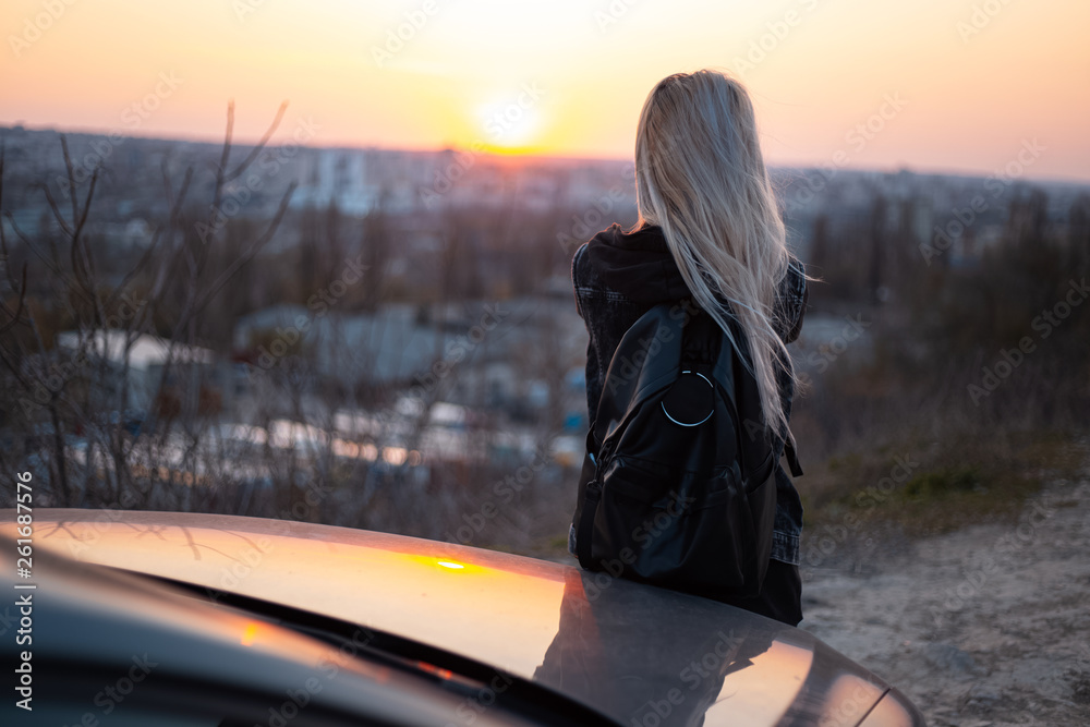 Back view of young girl with black backpack looks at the sunset. Stock ...