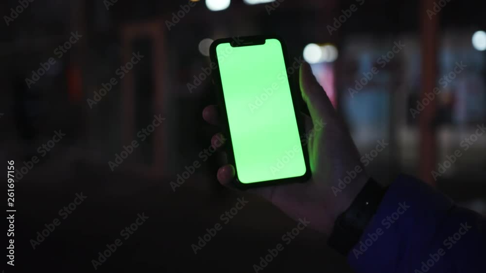 Man hand holding cellphone with blank green screen on blurred background of subway's exit. Touch ...
