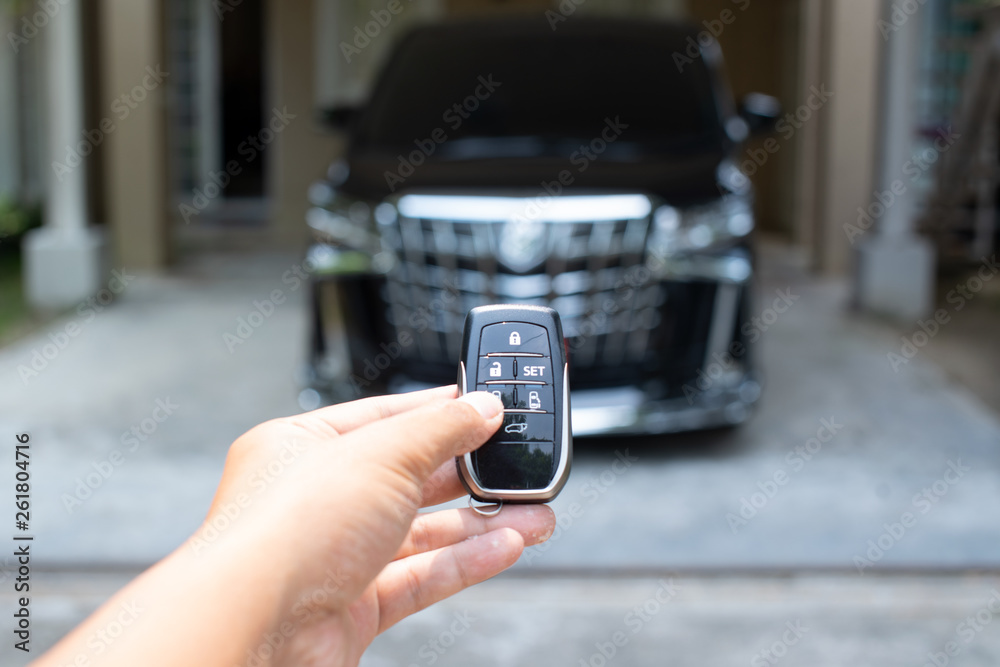 Men's hand holding car key ready to start a new car with blurred black ...