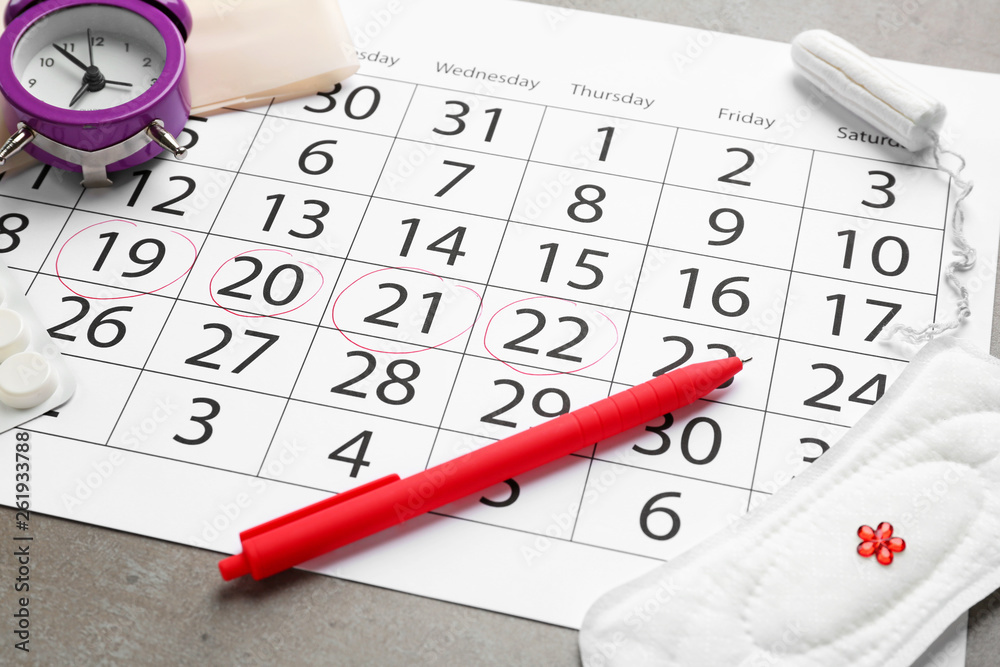 Menstrual calendar with feminine products and alarm clock on grey ...