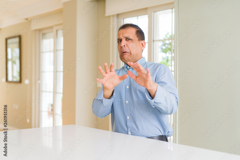 Middle age man sitting at home afraid and terrified with fear ...