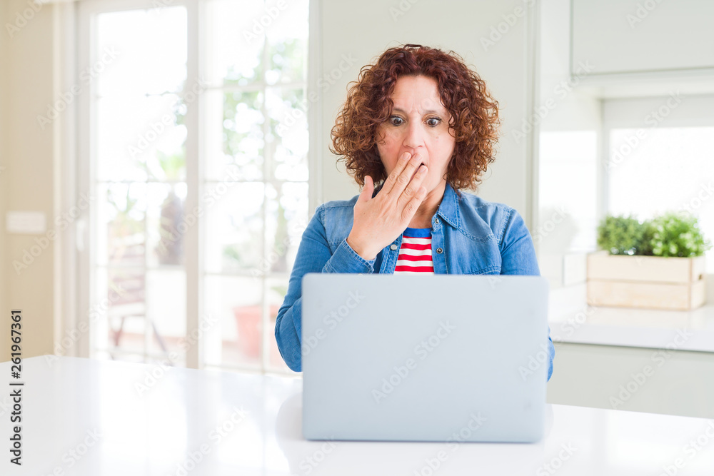 Senior woman working using computer laptop cover mouth with hand ...