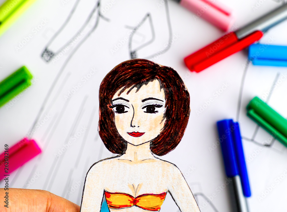 Paper doll in human hand against paper with drawing clothes and color ...