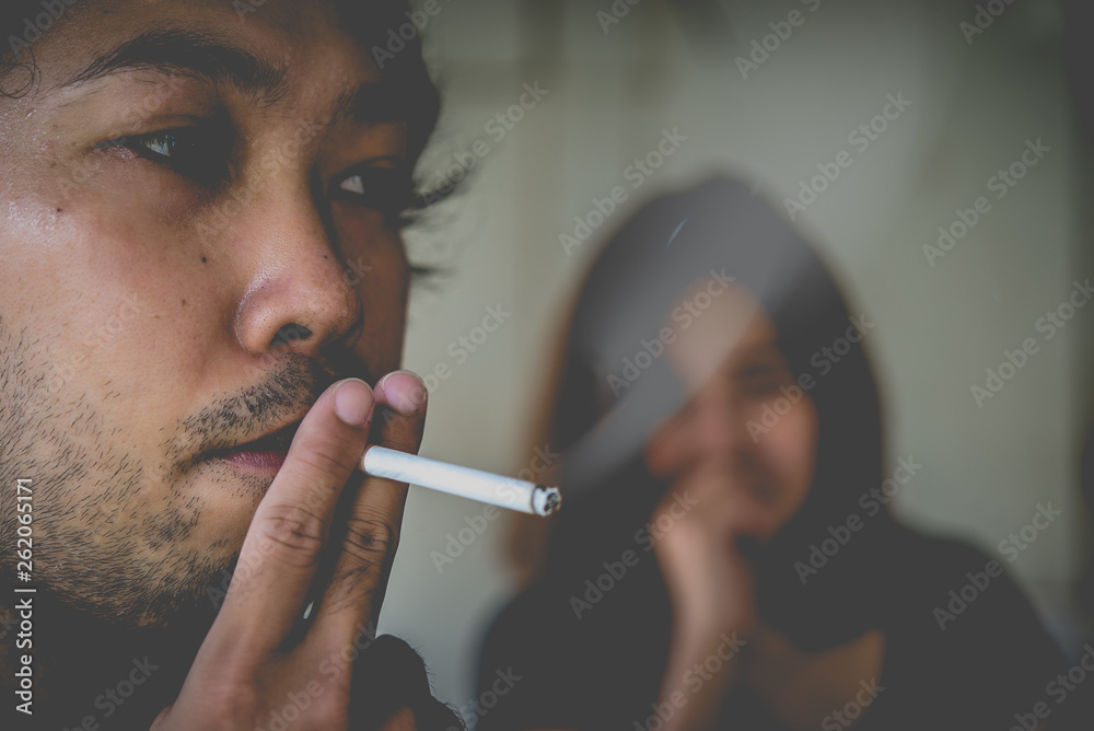 Passive smoking concept.Asian Man is smoking cigarette and woman is ...