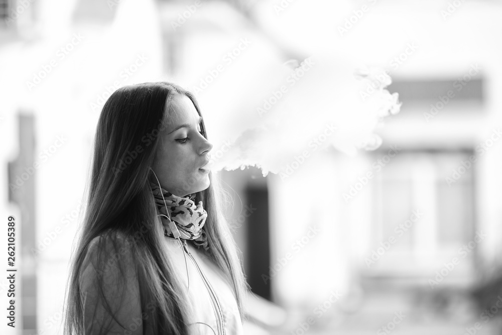 Vape teenager. Young pretty white girl in casual clothing smoking an ...