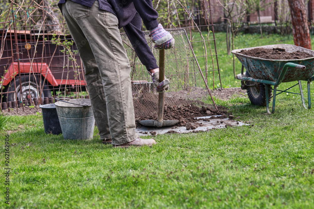 Summer worker is sifting soil through handmade sieve. Summer work ...