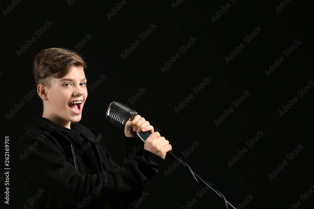 Teenage boy with microphone singing against dark background Stock Photo ...