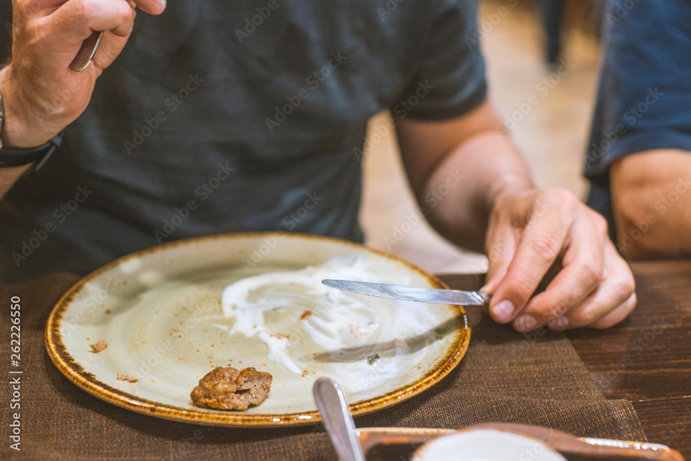 Man eating kebab with white sauce from clay plate in Middle Eastern ...