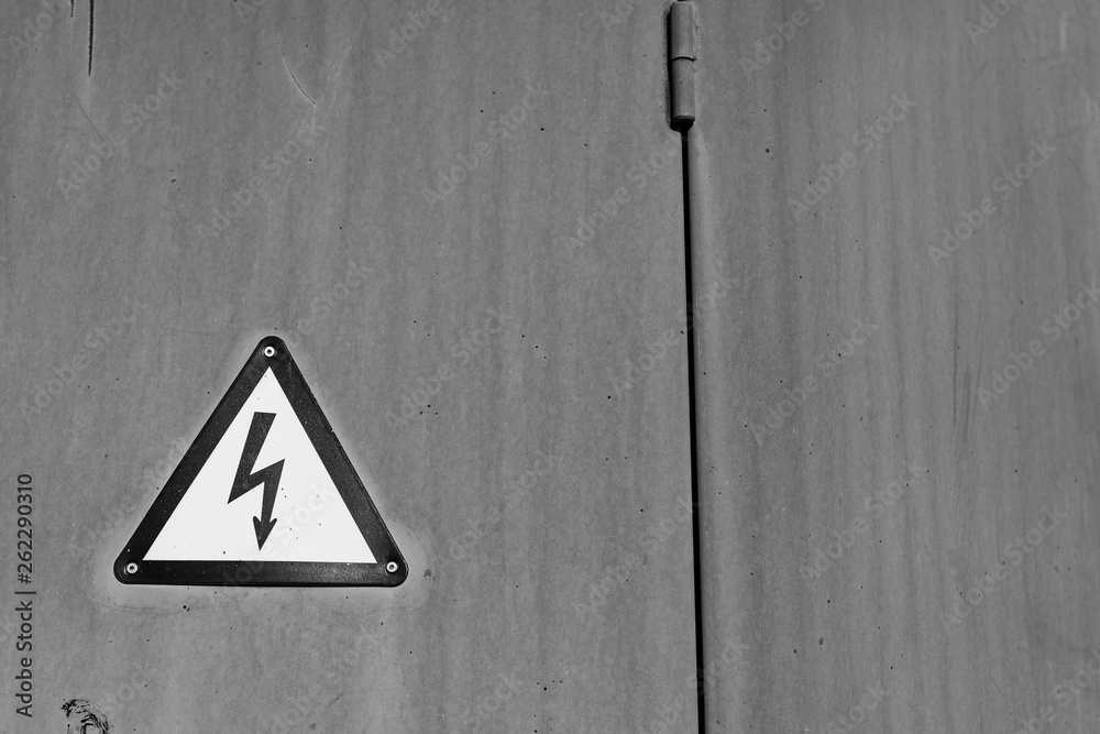 Locked electric panel with attention sign on the grey wall of ...