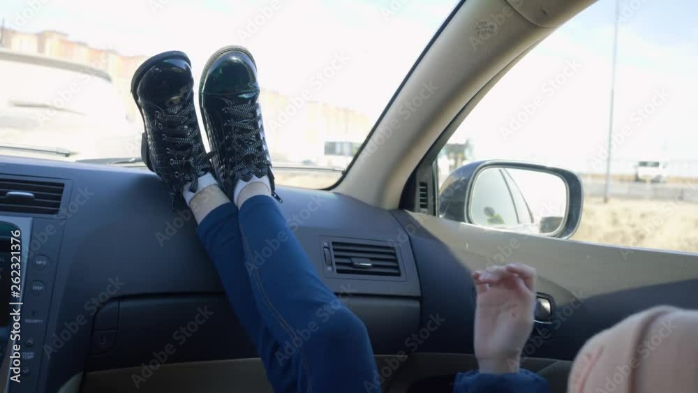 Legs of young girl lying on dashboard car moving to music beat on ...