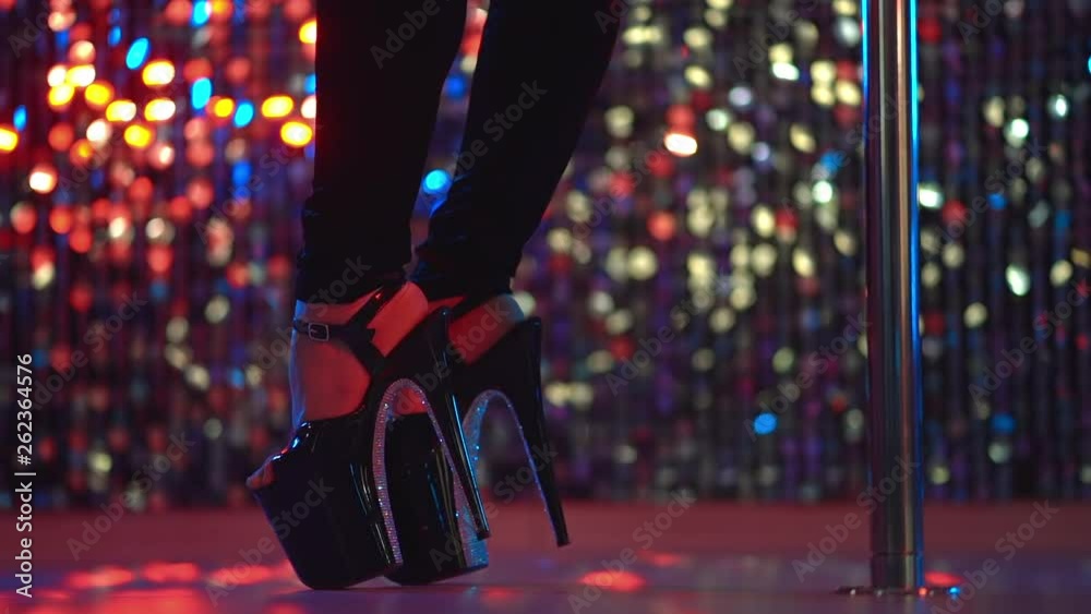 Young sexy striptease dancer moving in high heels shoes with rhinestones on stage with pylone in ...