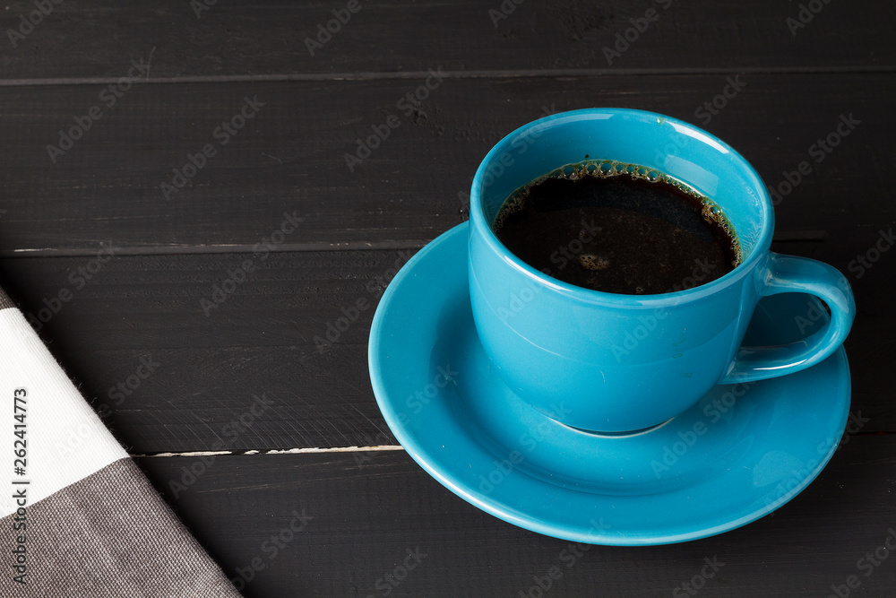 Cafe en taza azul con plato que le hace juego en fondo de madera negra ...