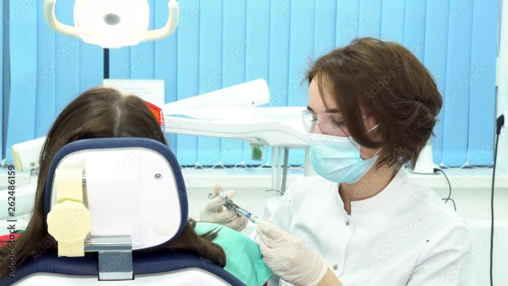 Rear view of female patient sitting in dental chair receiving an ...