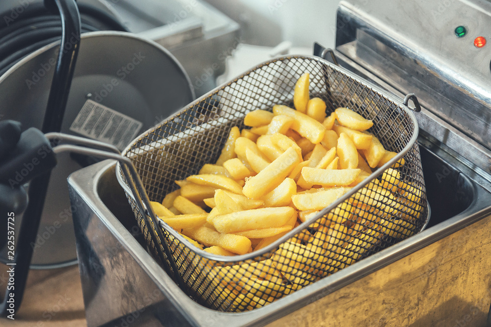 French fries cooking. Grid with strips of potato lowered into boiling ...