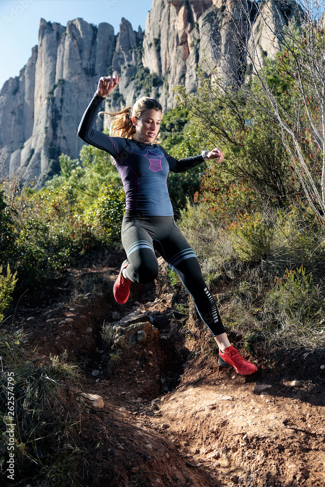 Young fitness woman trail runner running and jumping on rocky mountain ...