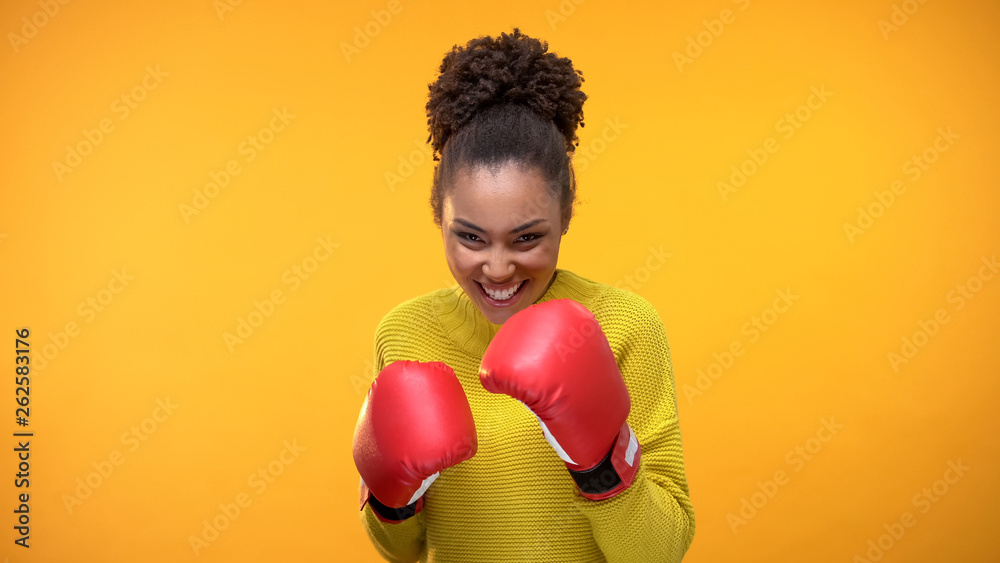 Smiling african teenager in boxing gloves imitating fight, having fun ...