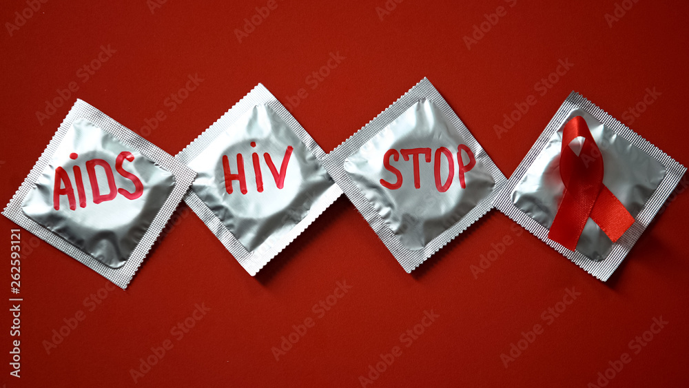 AIDS HIV stop words and red ribbon on condoms on red background ...