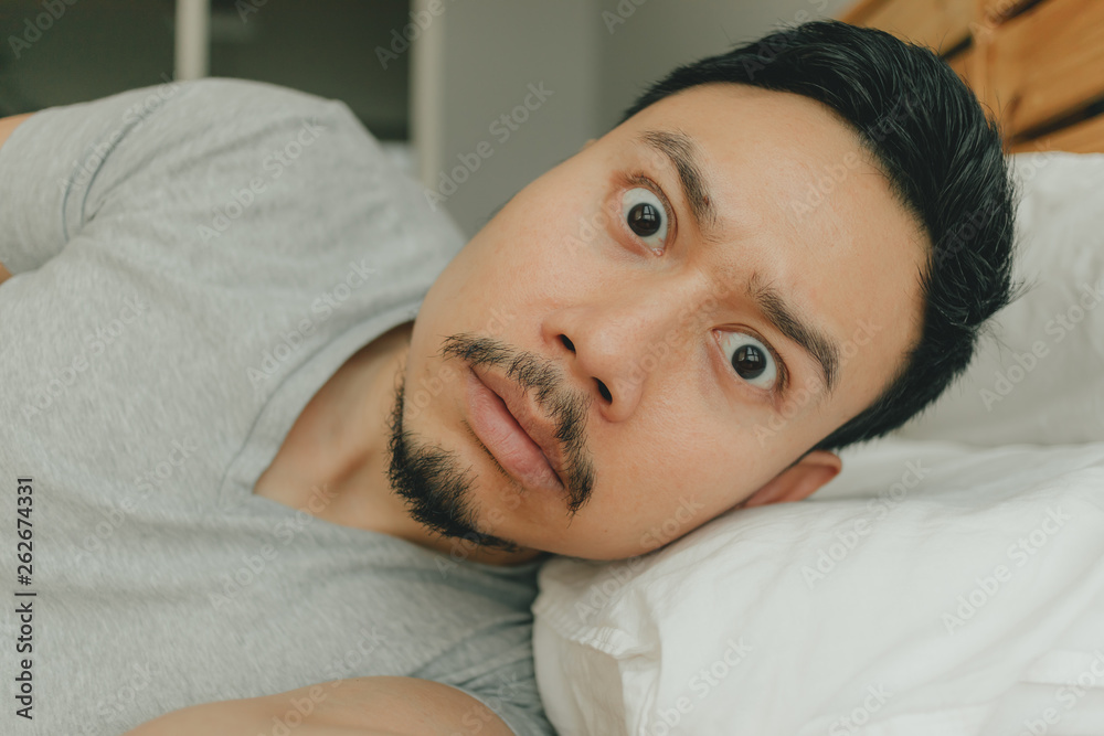 Close up man sleeping on his bed with shocked face. Concept of late ...