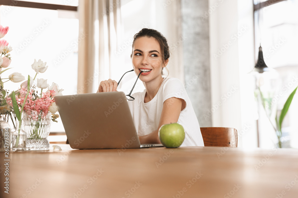 Beautiful young student girl sitting indoors using laptop computer ...