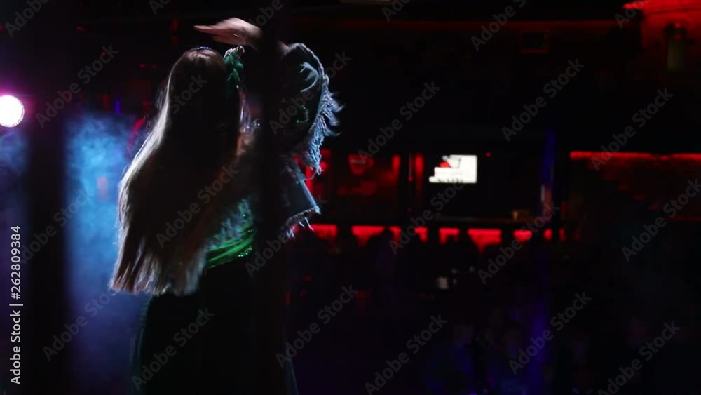 Girl who sings and dances on stage, Back view of singer. Light and ...