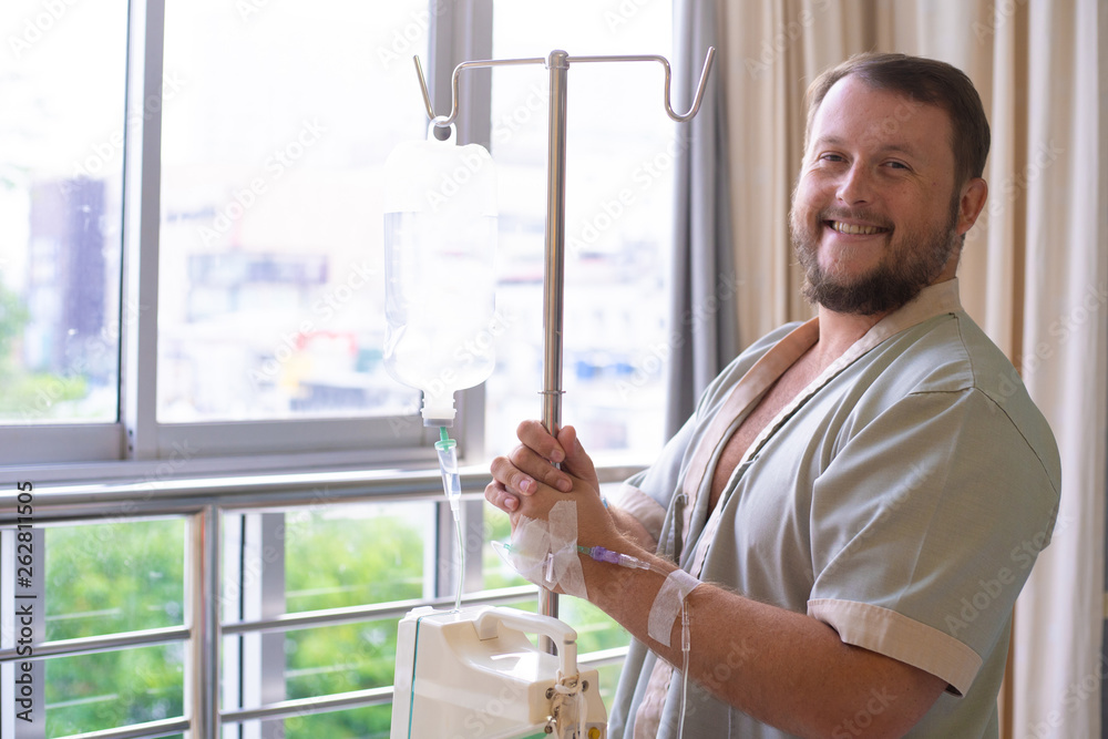 patient with a dropper looks out the window of the hospital room and ...