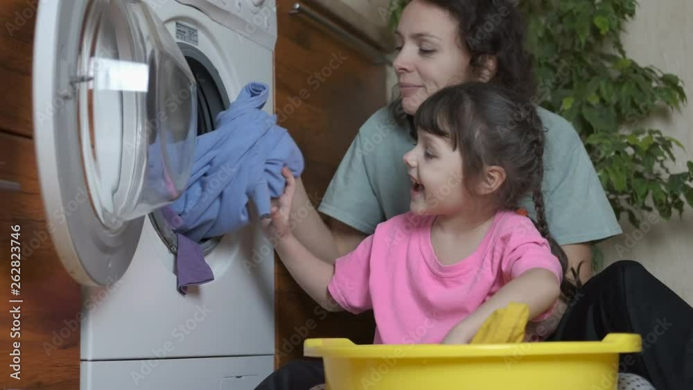 Mother and child wash clothes. Happy mom with her daughter at the ...