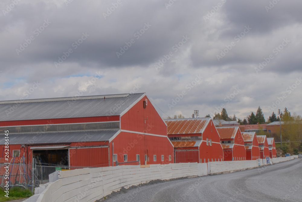 Red horse barns around a race track with white rail fence. Stock Photo ...