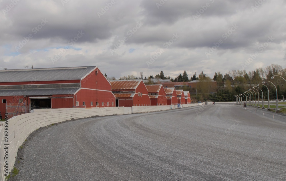 Red horse barns around a race track with white rail fence. Stock Photo ...