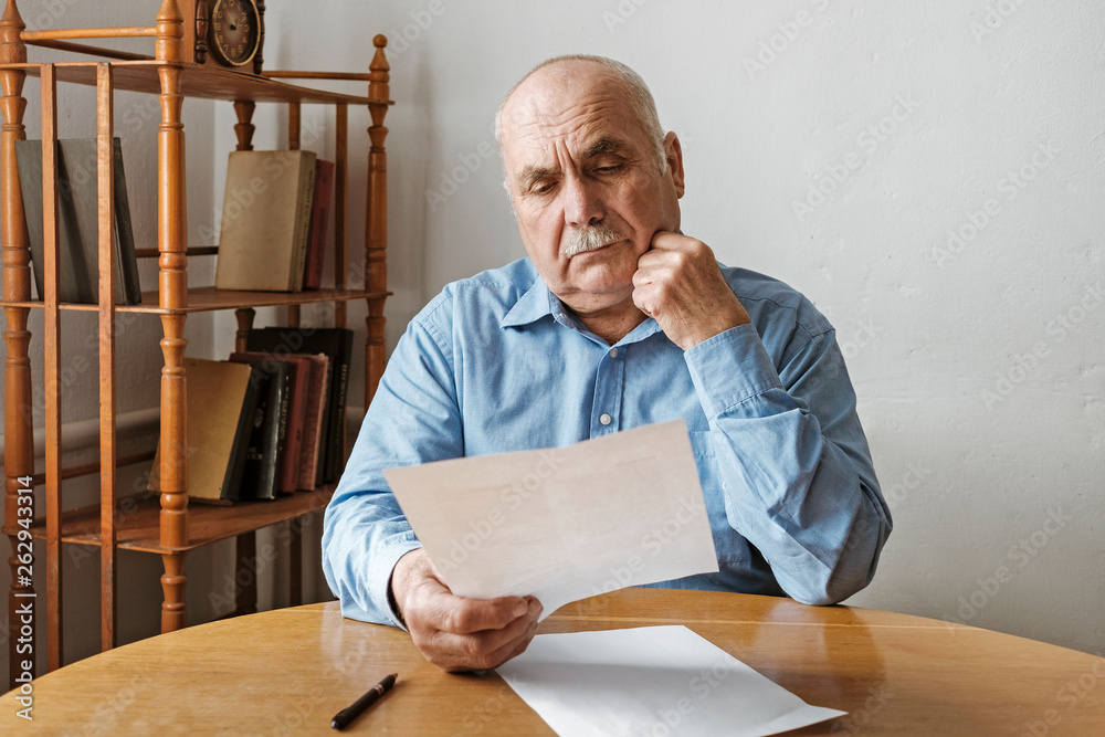 Thoughtful old man reading a paper document Stock Photo | Adobe Stock