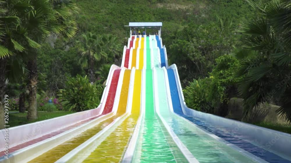 People sliding on colorful water slide at aquapark at summer vacation ...