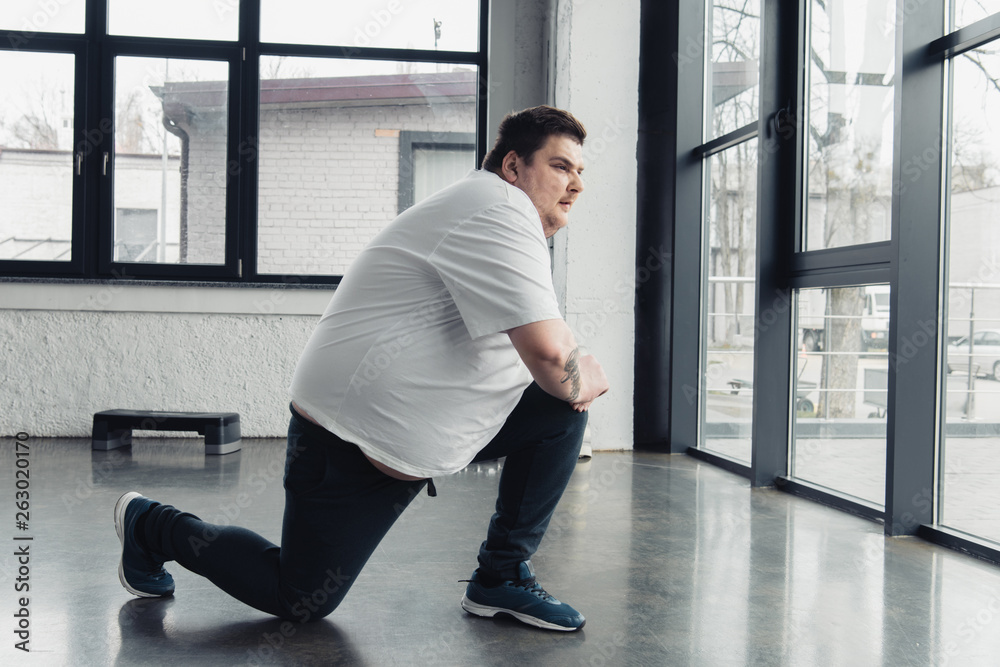 overweight man stretching legs at sports center with copy space Stock ...
