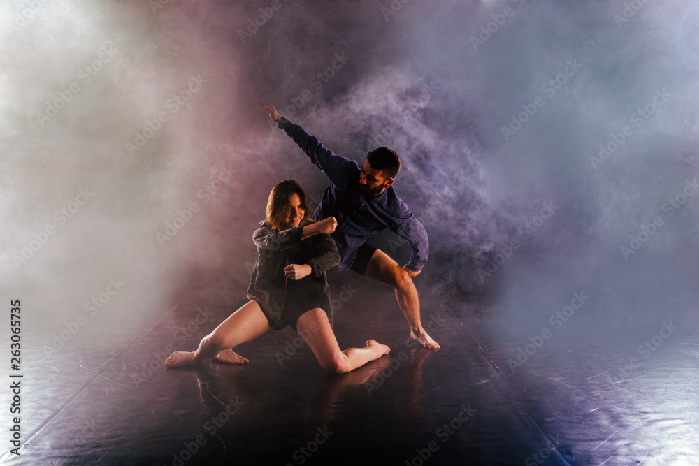 Modern dance couple twisting their legs and lening close to the ground ...