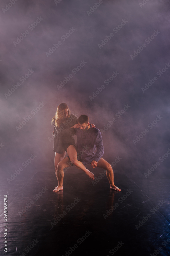 Modern dance couple twisting their legs and lening close to the ground ...