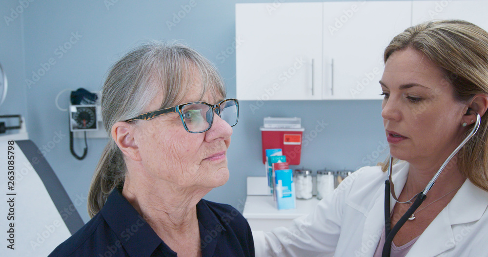 Female doctor using stethoscope on senior woman patient. Older woman ...