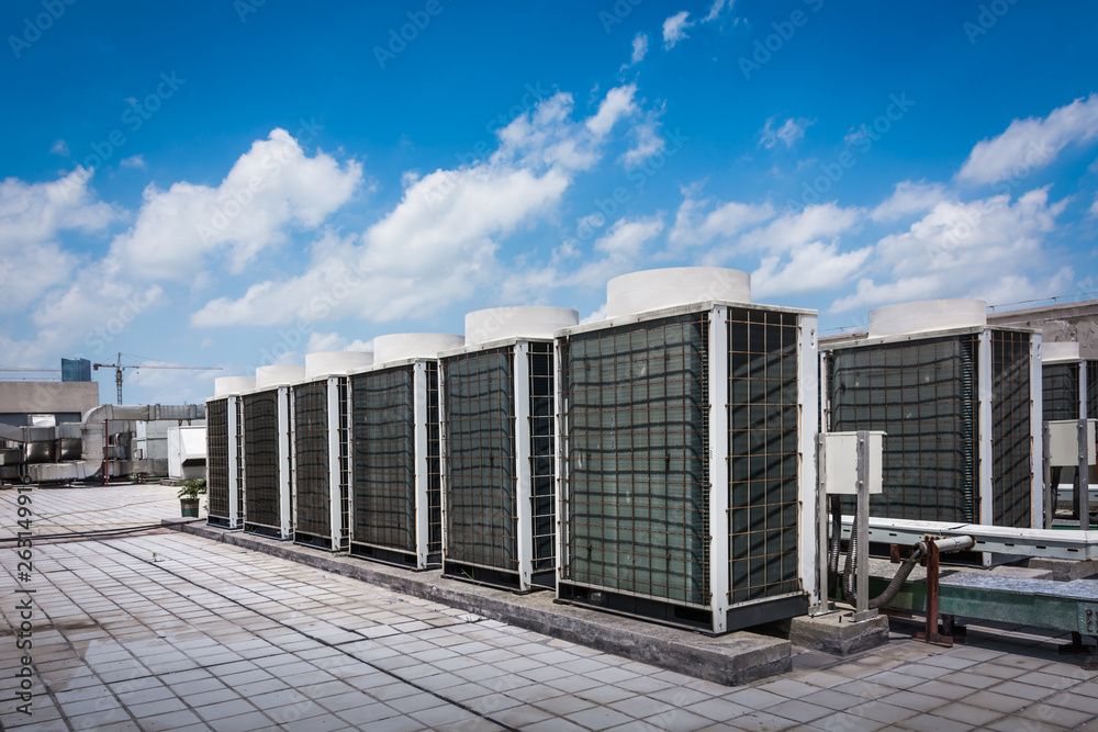 Square air-conditioning unit on the roof with a round fan. In the ...