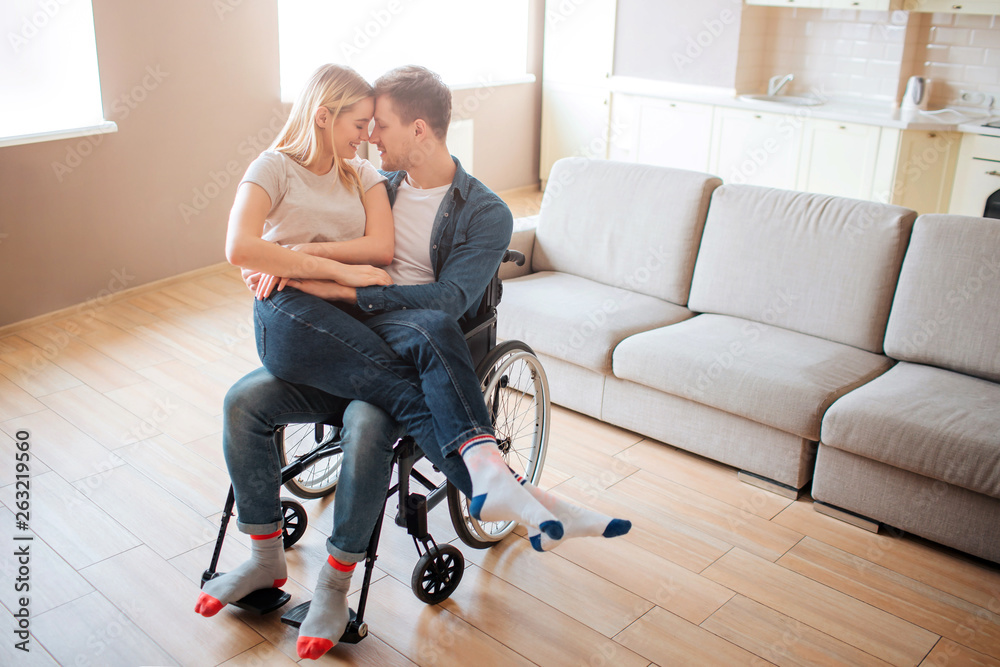 Young man with disability and special needs holding girlfriend on knees ...