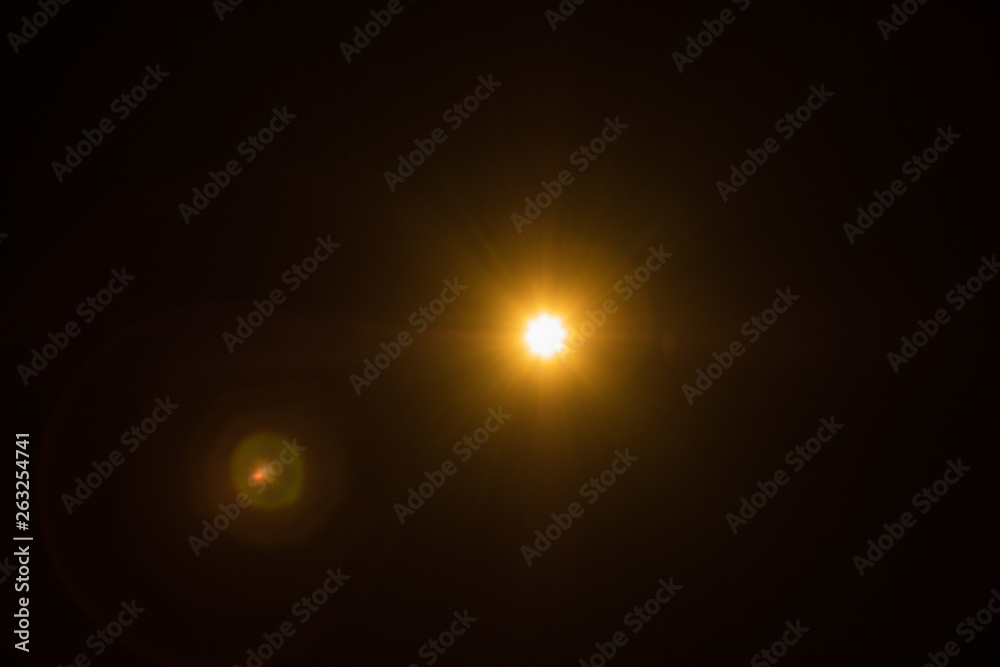 Yellow flash spark on black background. Lens flare effect. Defocused ...