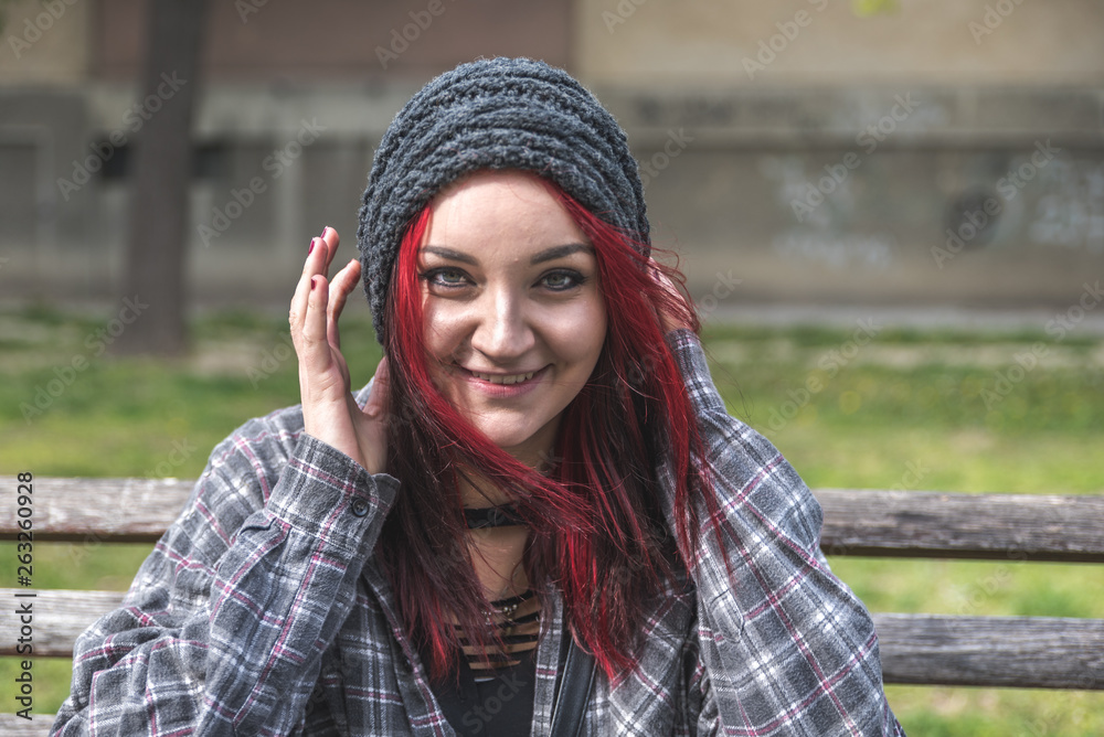 Positive smiling homeless red hair girl sitting on the bench on the ...