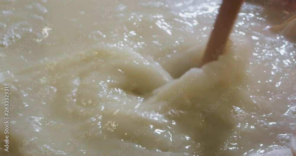 Slow motion close up of a cheesemakers are preparing a form of Parmesan ...